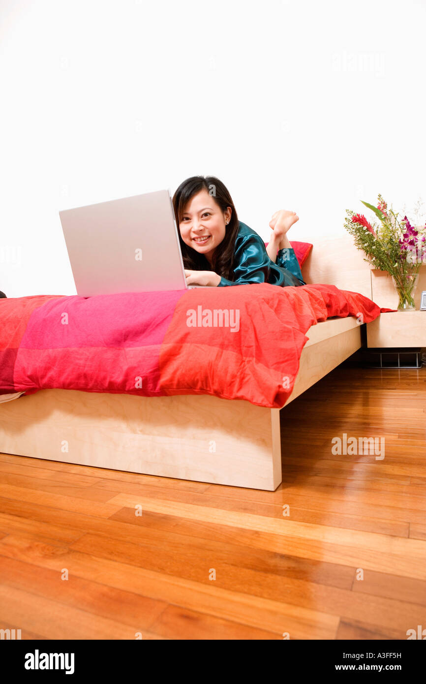Portrait of a young woman lying down and using a laptop Stock Photo - Alamy