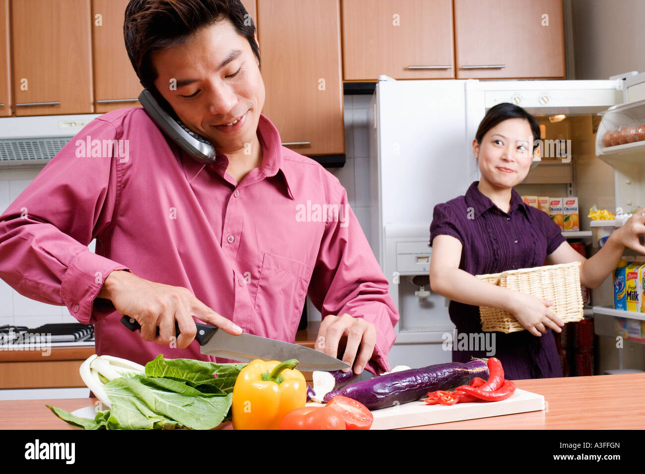 Close-up of a mid adult man cutting vegetables while talking on a ...