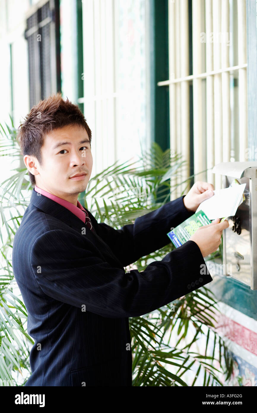Portrait of a businessman dropping mails into a mailbox Stock Photo - Alamy