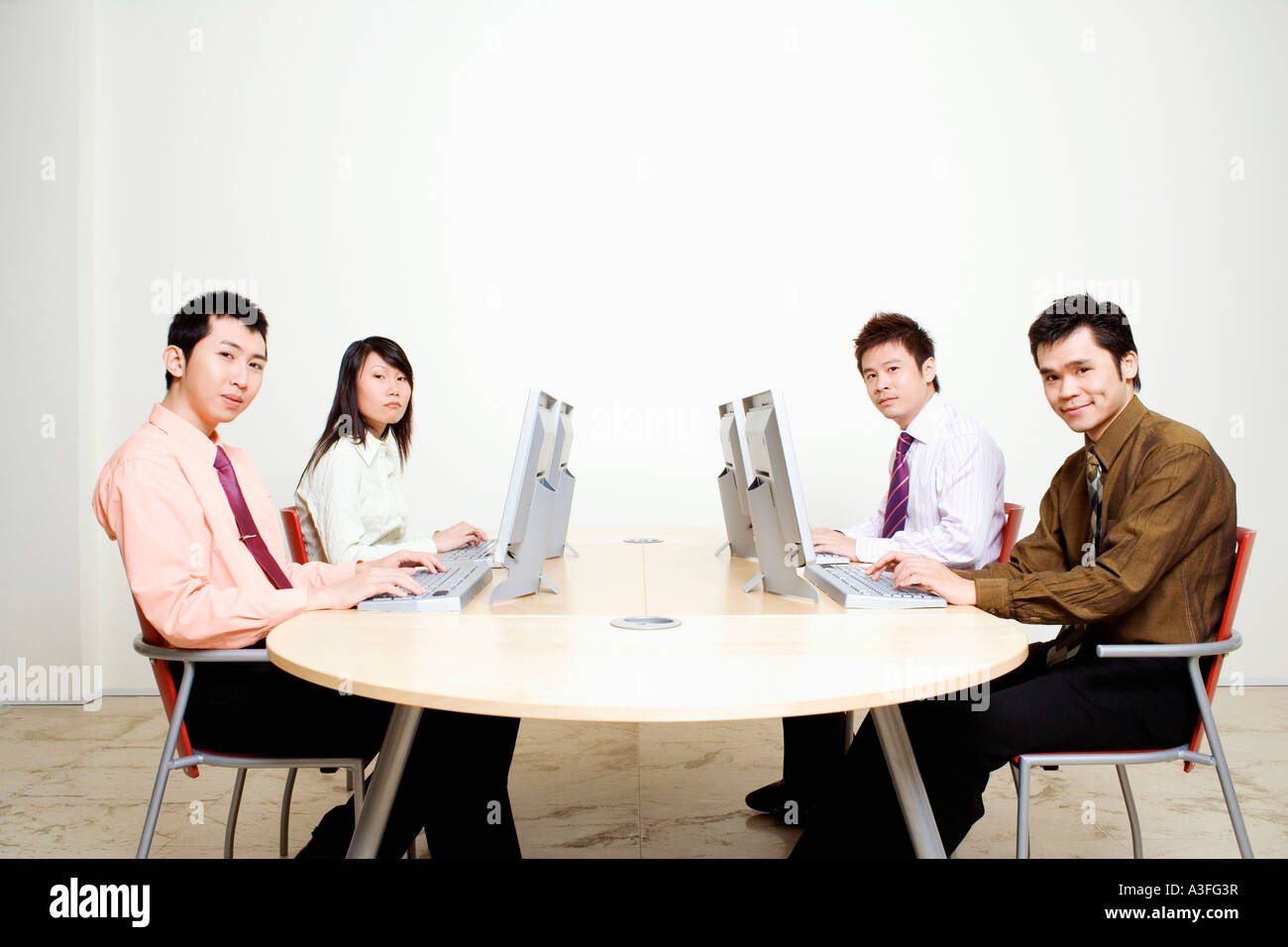 Portrait of three businessmen with a businesswoman working on computers ...