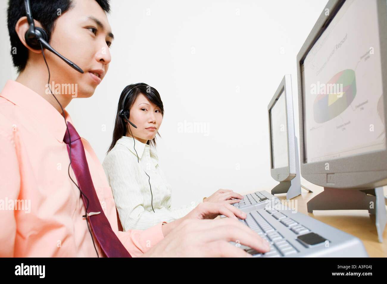 Two customer service representatives working on a computer Stock Photo ...