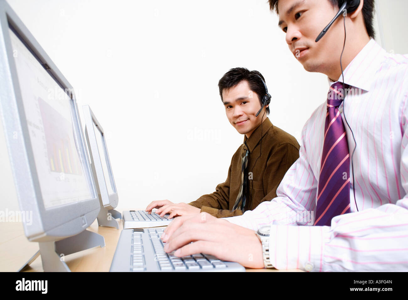 Two customer service representatives working on a computer Stock Photo ...