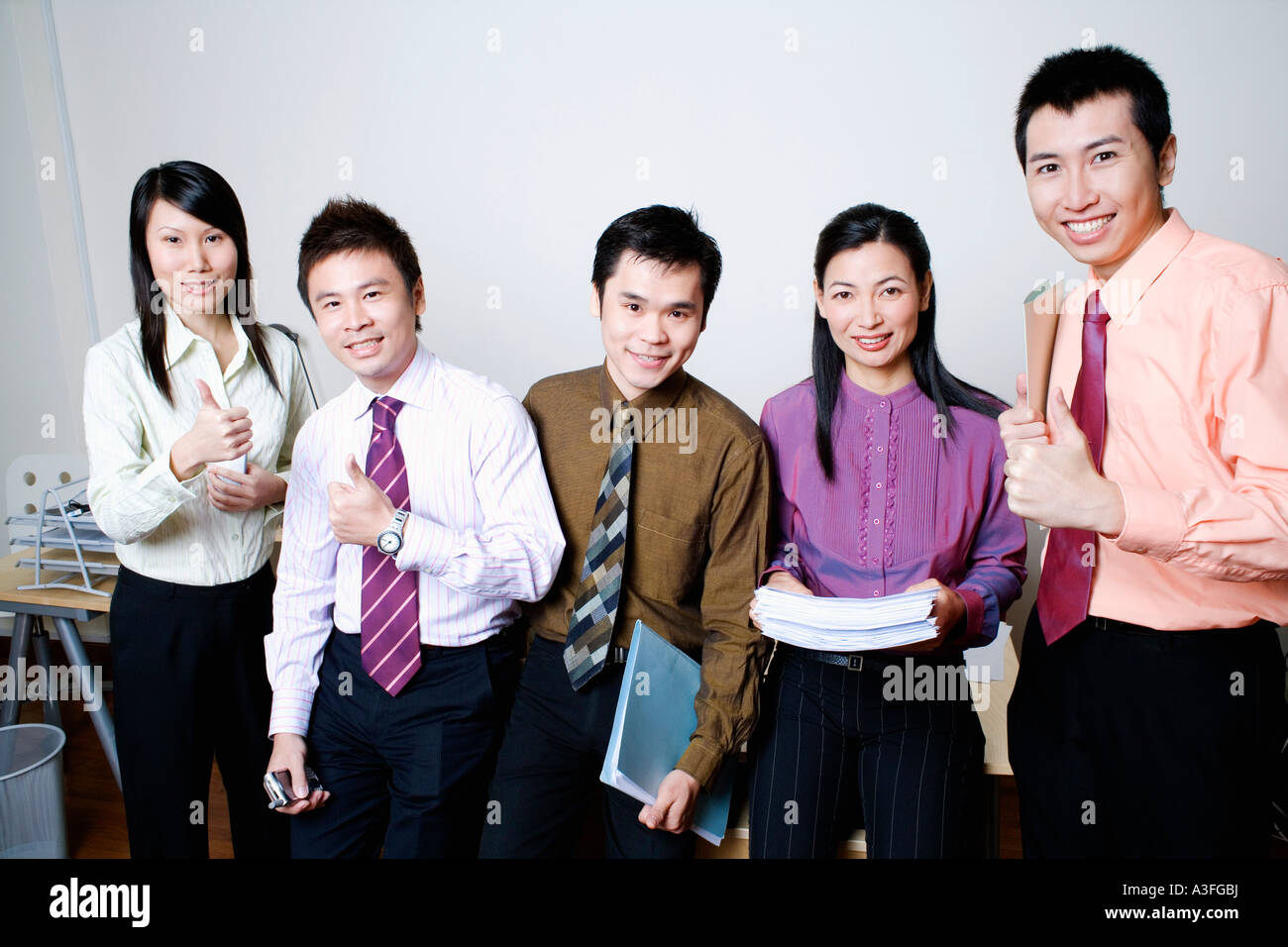 Portrait of five business executives standing and smiling together ...
