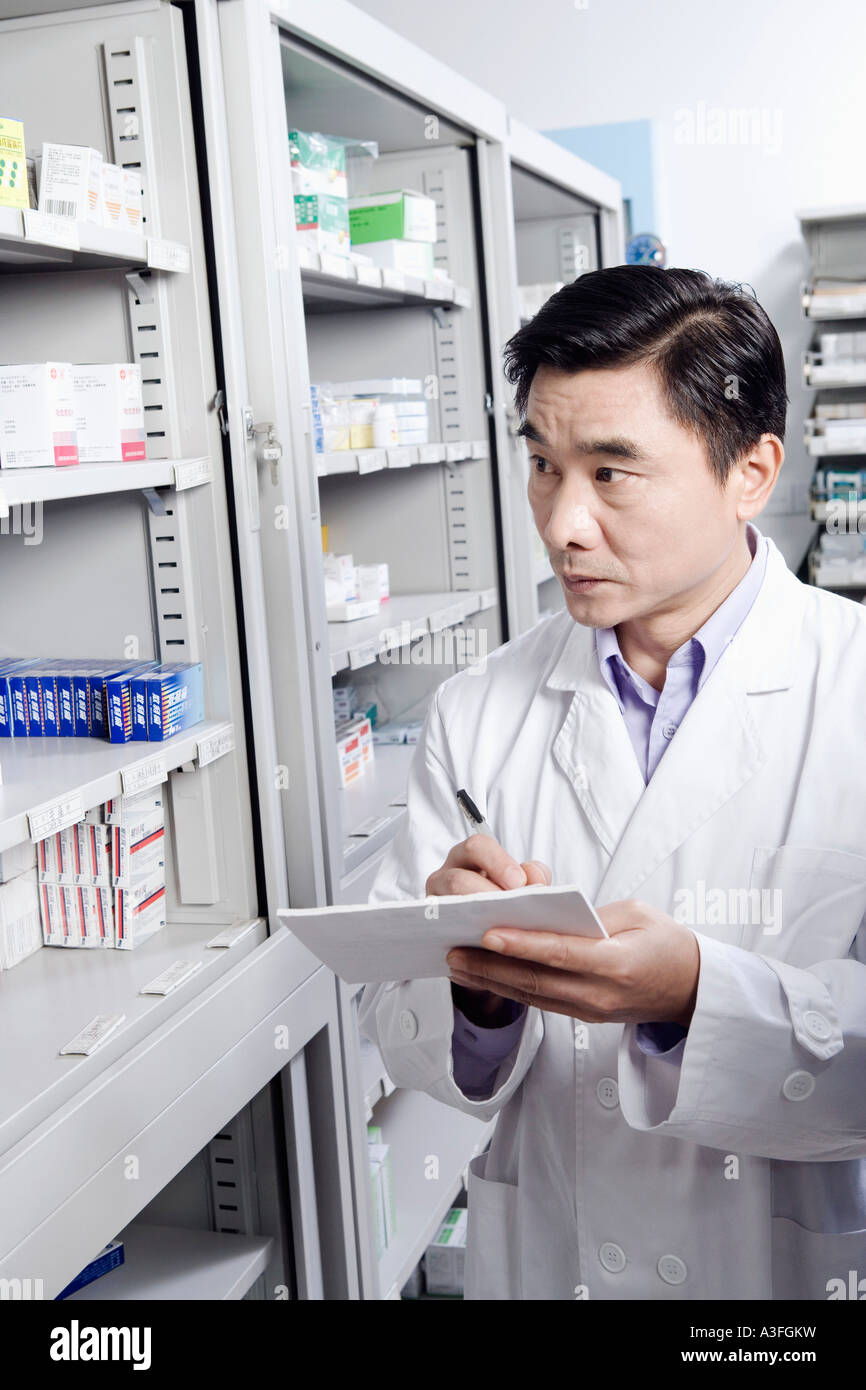Male pharmacist writing in a store room Stock Photo - Alamy