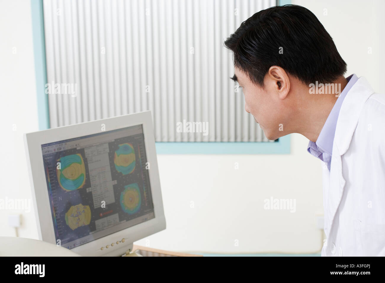 Side profile of a male doctor looking at a computer monitor Stock Photo ...