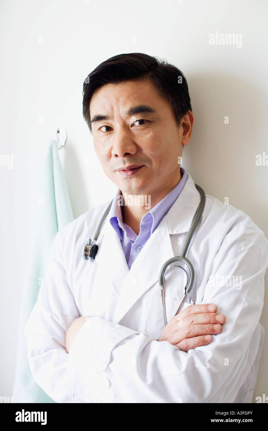 Portrait of a male doctor leaning against a wall Stock Photo - Alamy