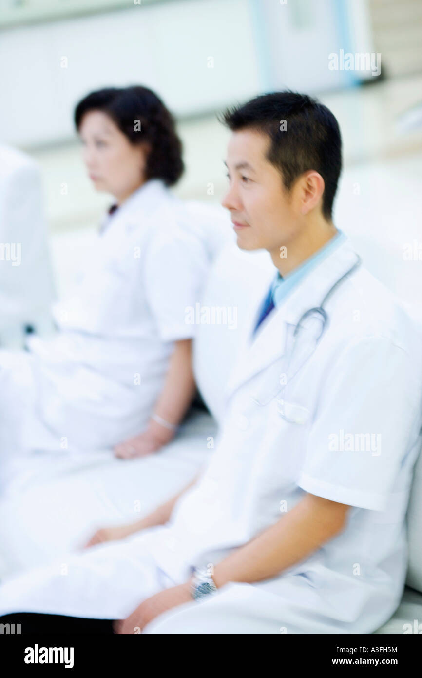 Side profile of a male doctor sitting on a couch with a female doctor ...