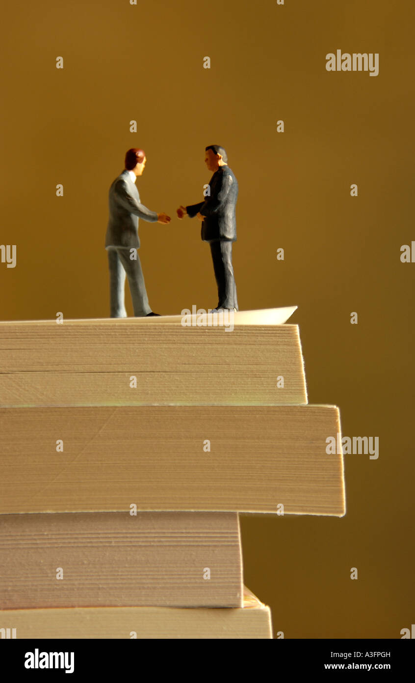 Figurines shaking hands standing on pile of books - publishing ...