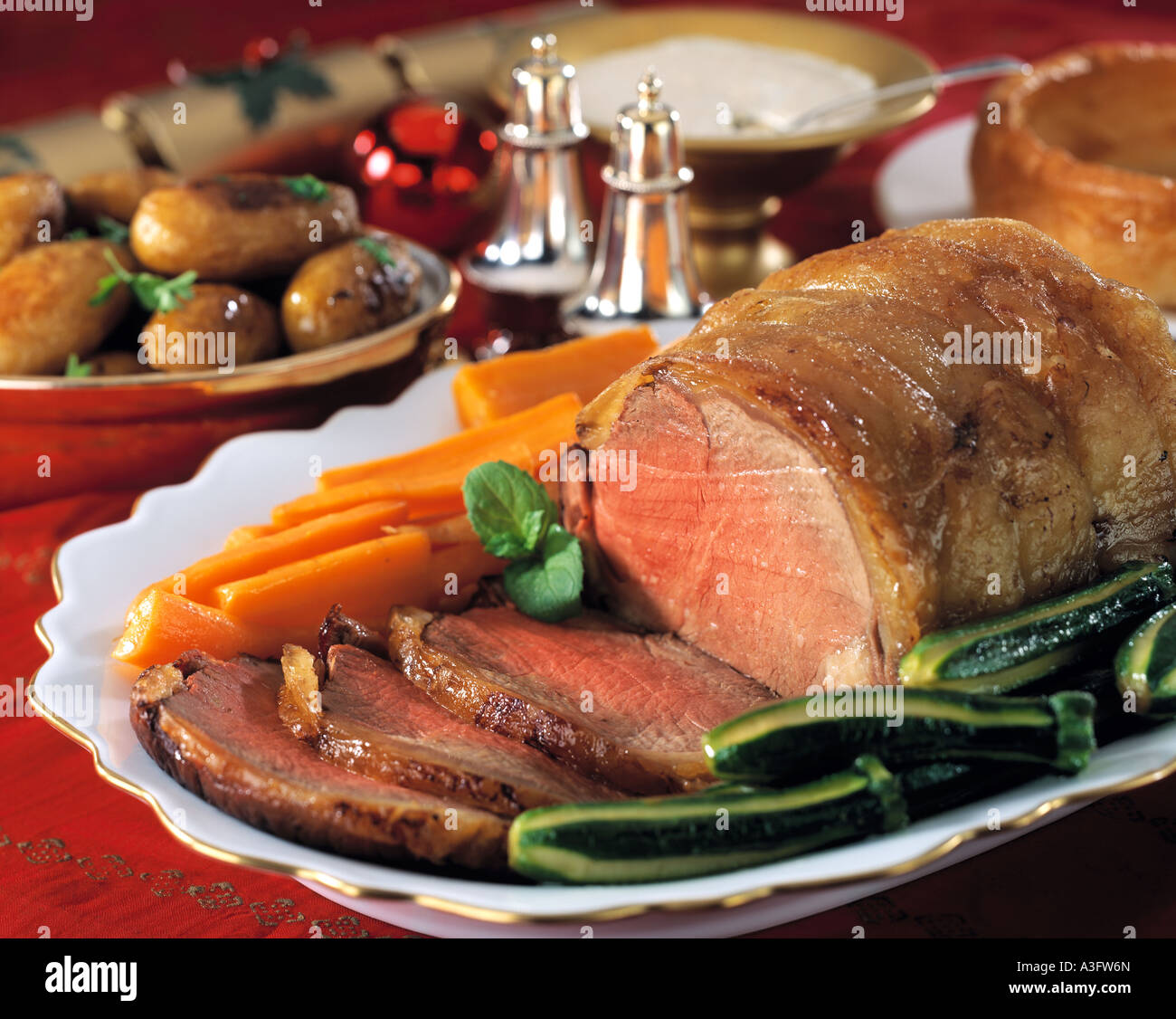 A whole roast beef with slices in a festive table setting editorial ...