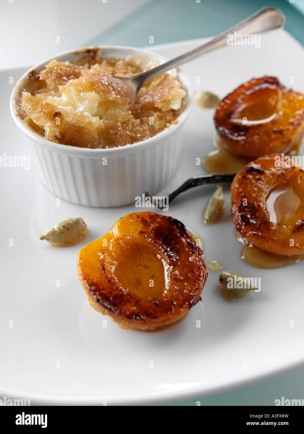 A ramekin of rice pudding with char grilled apricots on a white plate ...