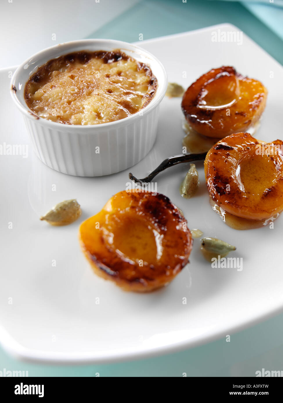 A ramekin of rice pudding with char grilled apricots on a white plate ...