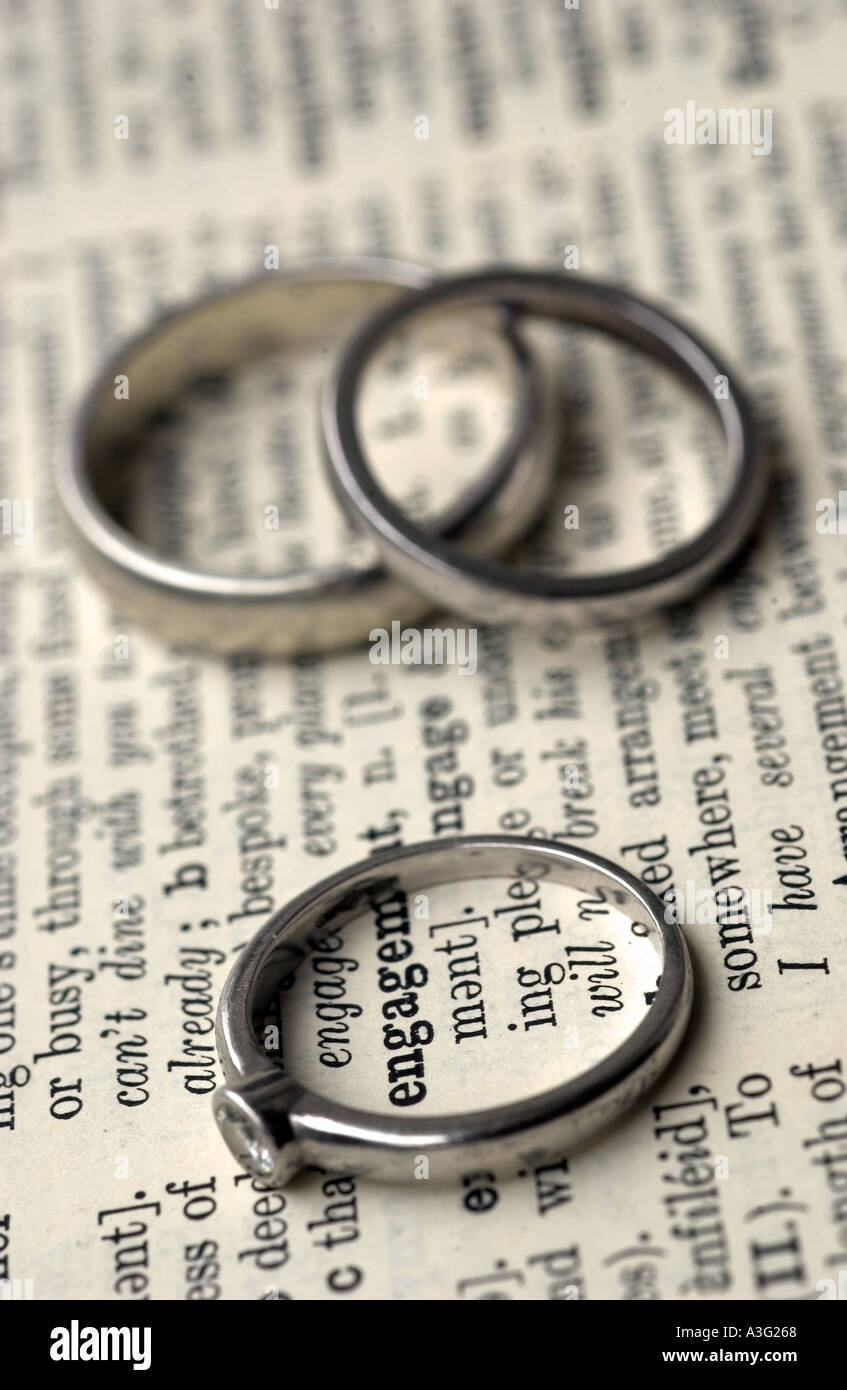Engagement and wedding rings on a dictionary showing the word engage ...
