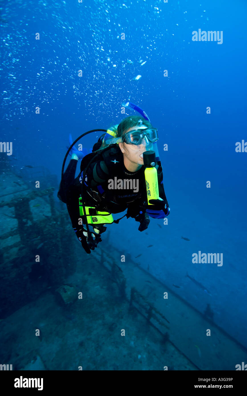 A FEMALE SCUBA DIVER HEADS FOR HE SURFACE BREATHING FROM A SMALL BAIL ...