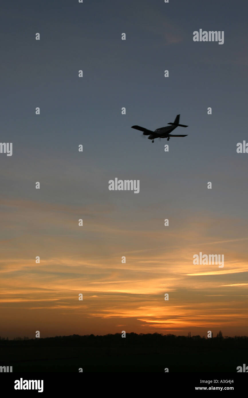 A light aircraft flying towards a setting sun Stock Photo - Alamy