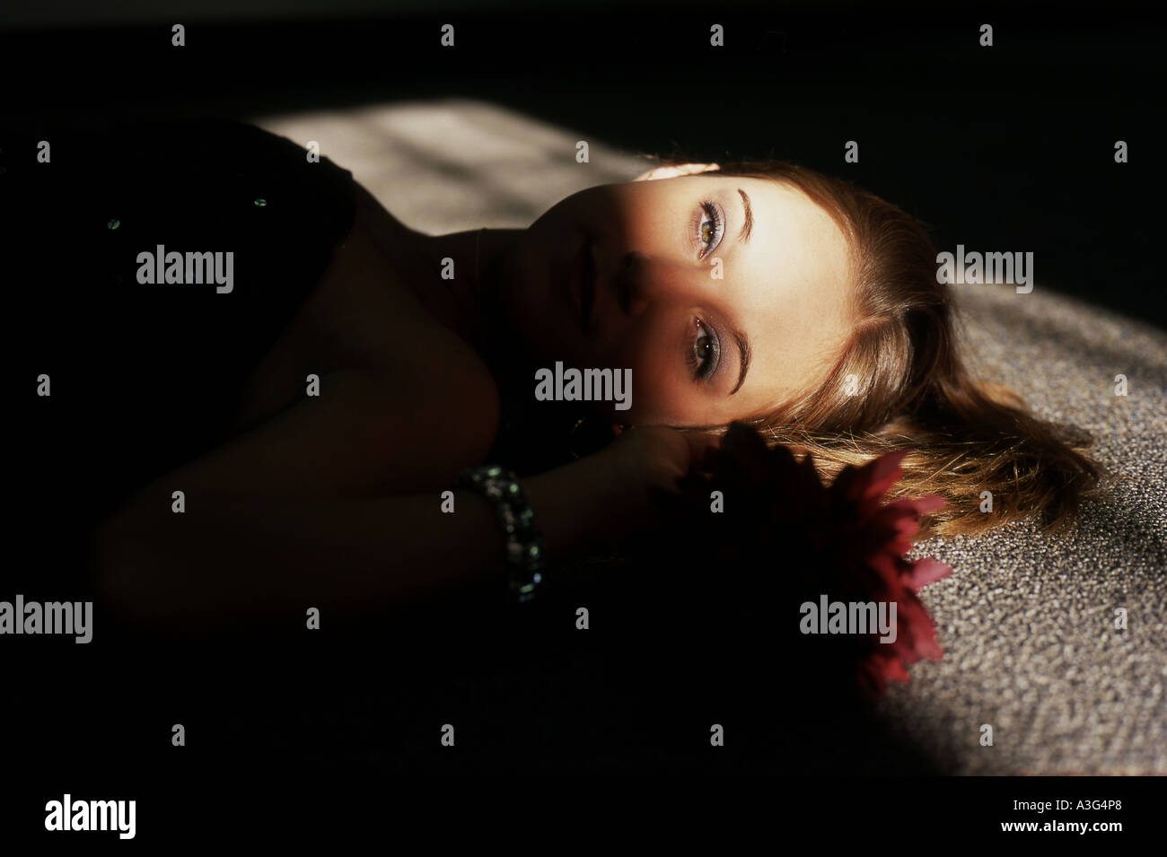 A young woman lying in a ray of light Stock Photo - Alamy