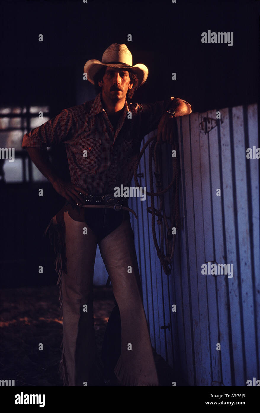 Partial silhouette of cowhand with hat and mustache whose arm rests on ...