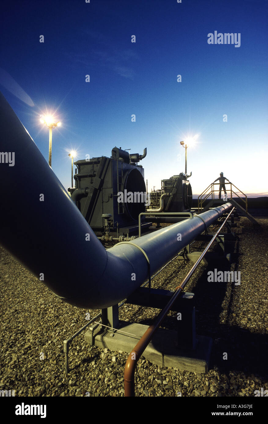 A close up of a bend in large blue pipeline running across gravel where ...