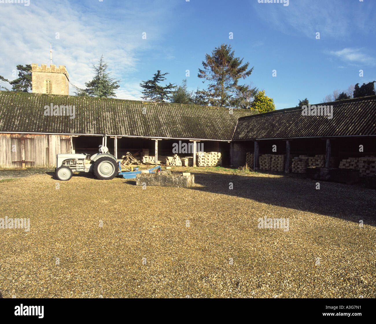 Old classic farm tractor standing in front of former farm buildings ...