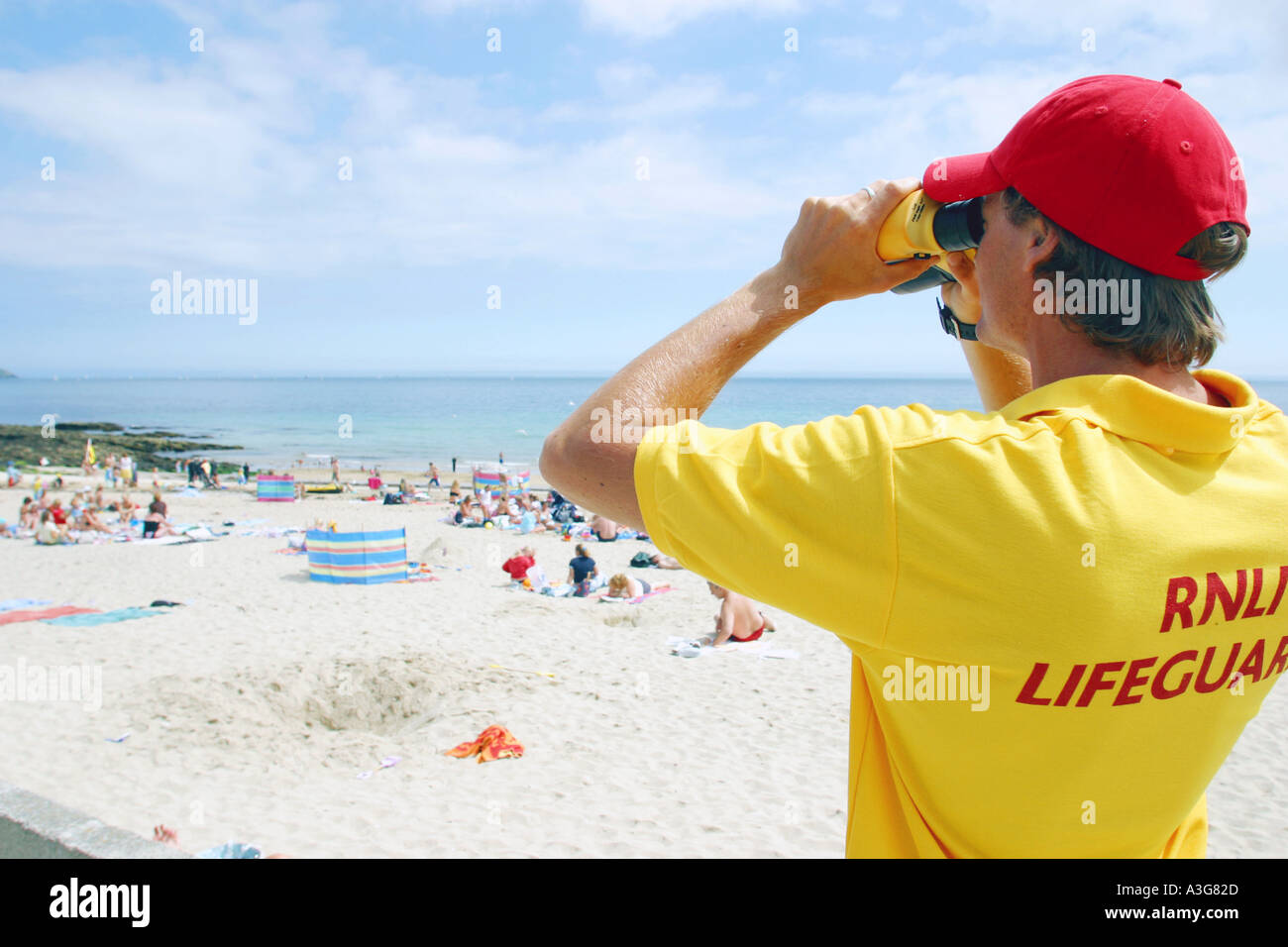 RNLI Beach Lifeguard surveys the beach at Gyllynvase Falmouth Cornwall ...
