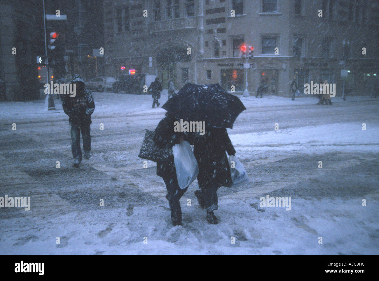 Two shoppers shelter under an umbrella during a severe thundersnow ...