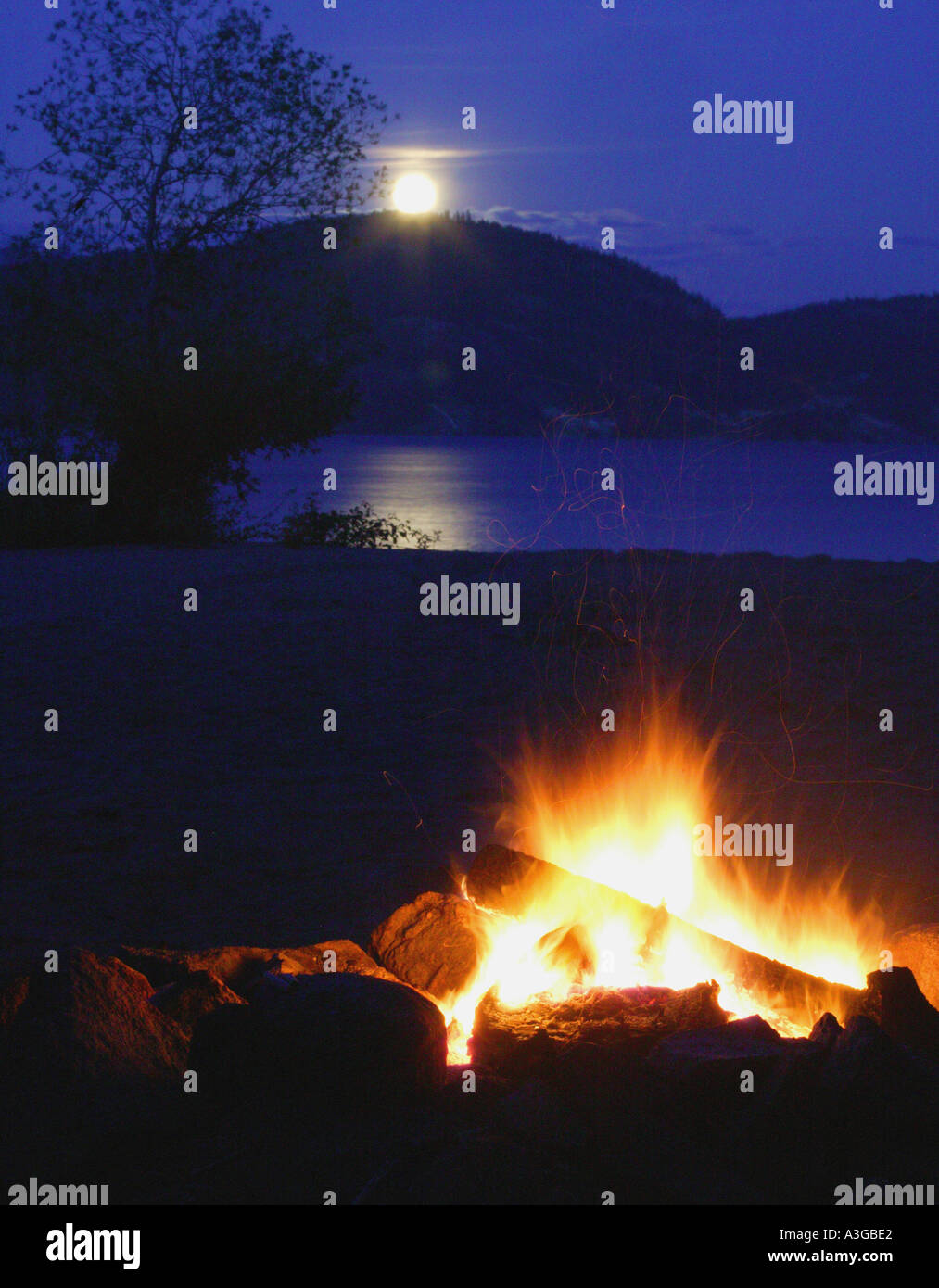 Moon rising by a bonfire Stock Photo - Alamy