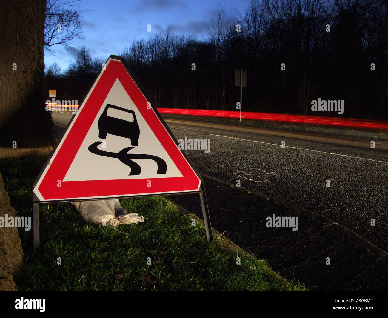 slippery road sign with fast traffic at night Stock Photo - Alamy