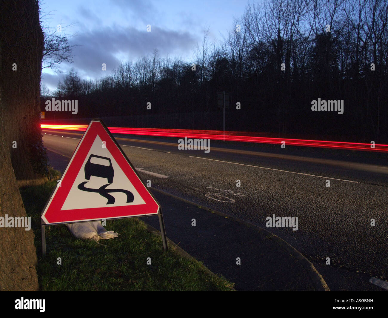 slippery road sign with fast traffic at night Stock Photo - Alamy