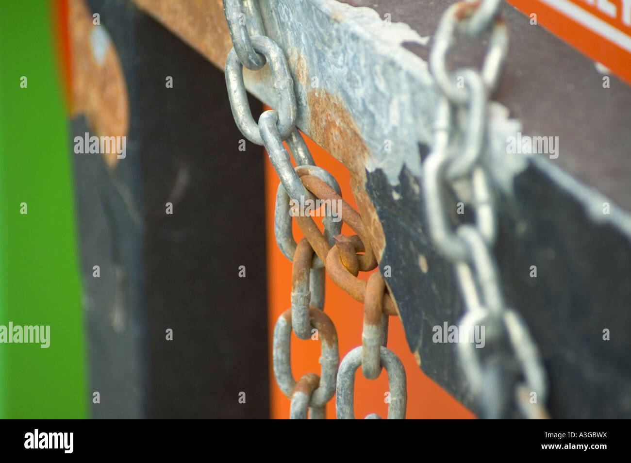 Chain hanging over rusty railing and colorful boxes Stock Photo - Alamy