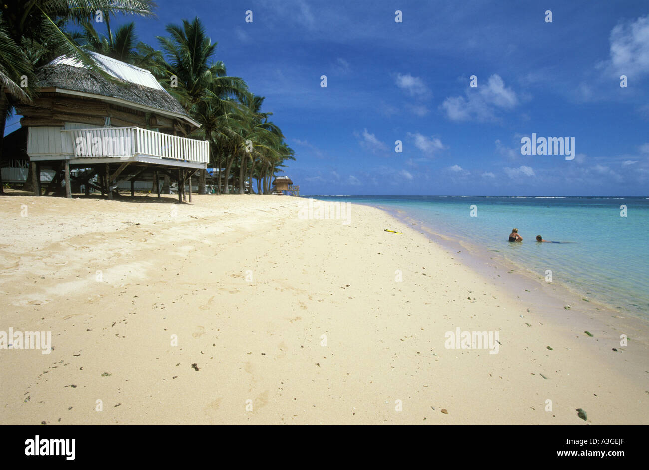 Beach fales and two tourists who relax in the water at Jane s Beach ...