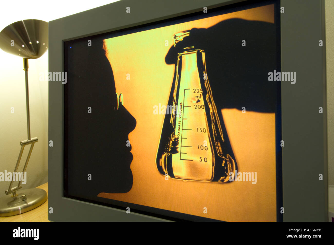 Technician holding beaker image displayed in color on office computer ...