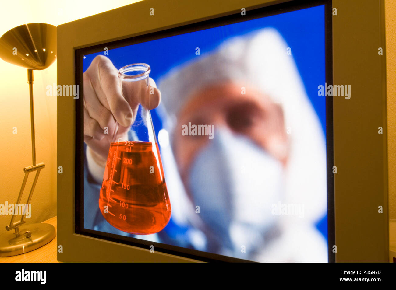 Technician holding beaker image displayed in color on office computer ...