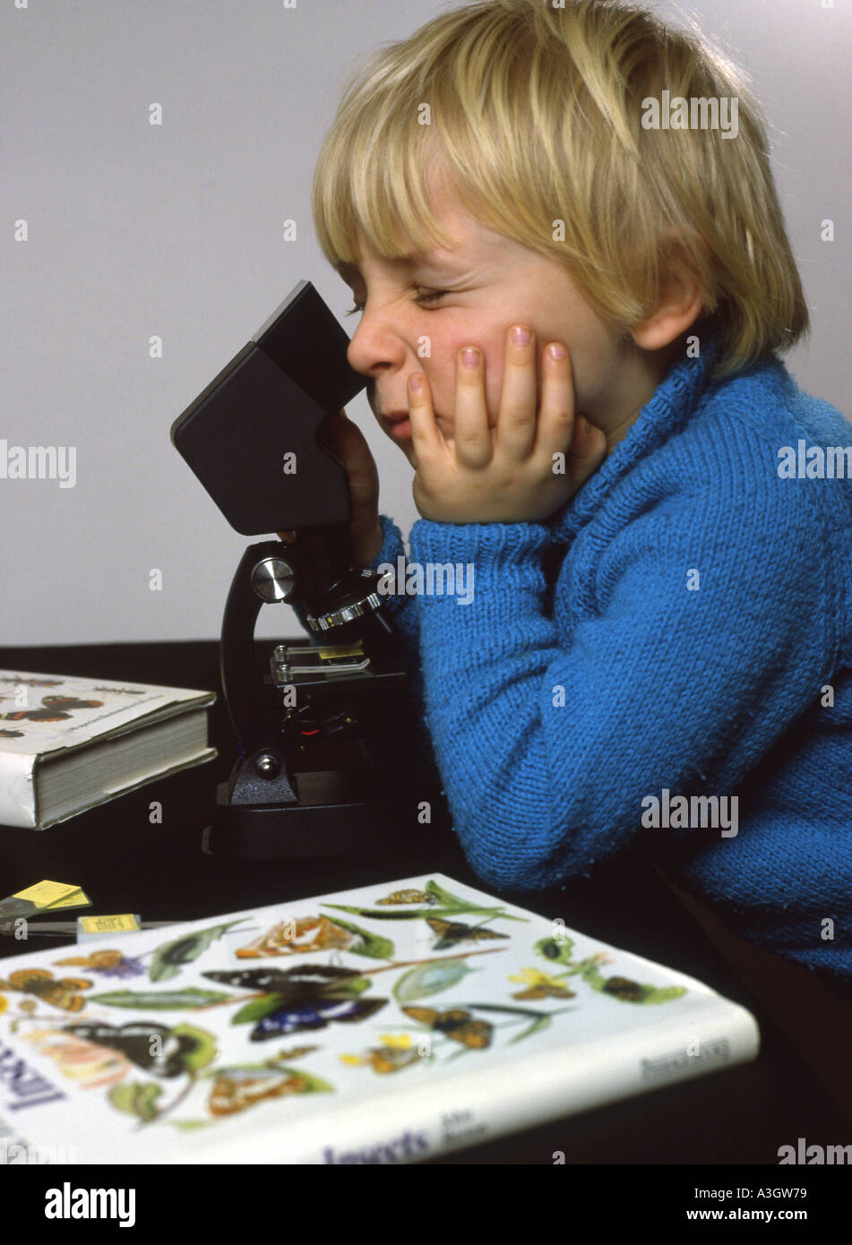 Young male child studying small object with microscope at home Stock ...