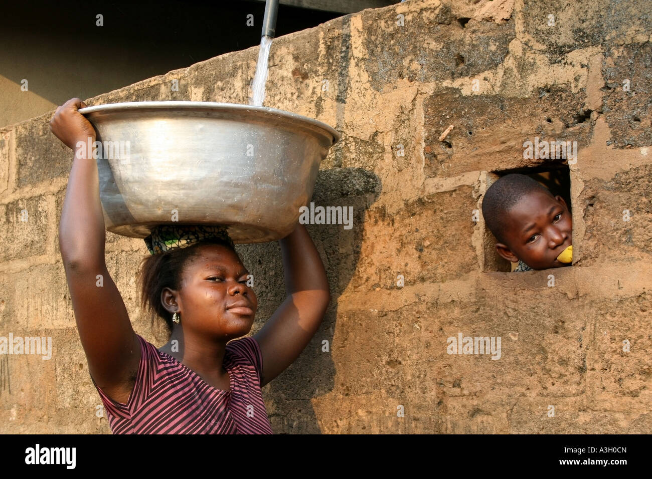 Lady collecting water from a communal pipe , Abomey , Benin Stock Photo ...