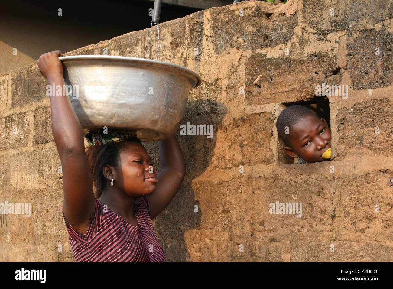 Lady collecting water from a communal pipe , Abomey , Benin Stock Photo ...