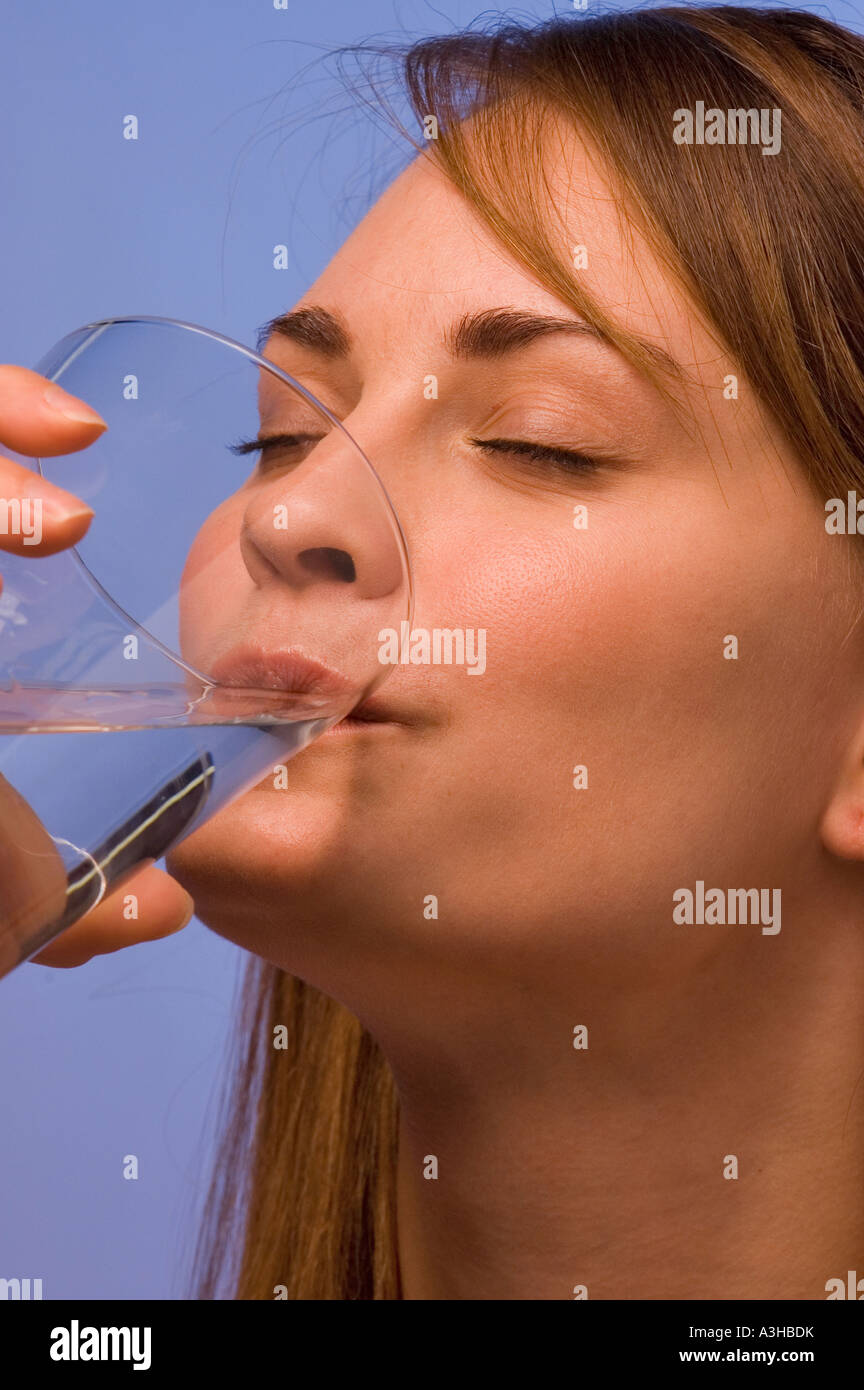 Woman hydrating after a workout by drinking water from a clear glass ...