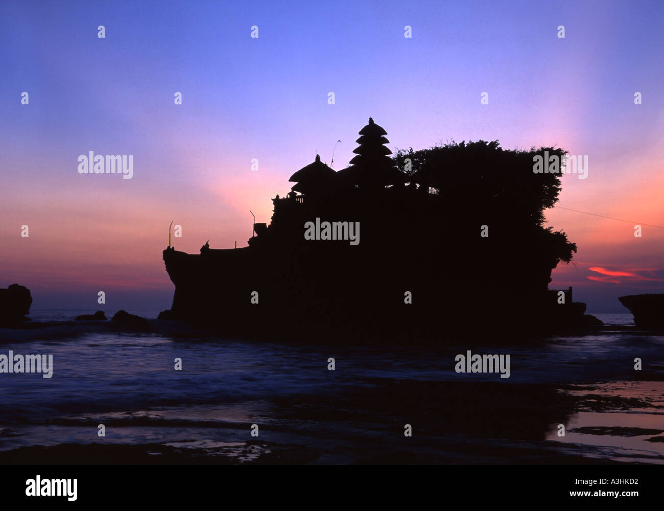 Shafts of light from a beautiful sunset appear from behind the rock and ...