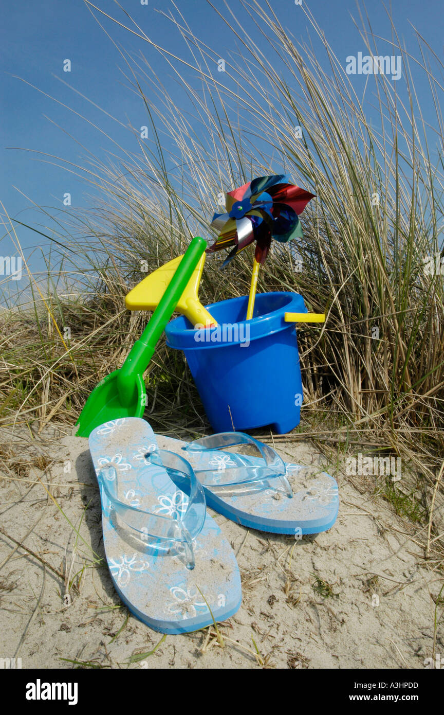 Flip flops with a bucket, spade and a sand castle windmill on the beach ...