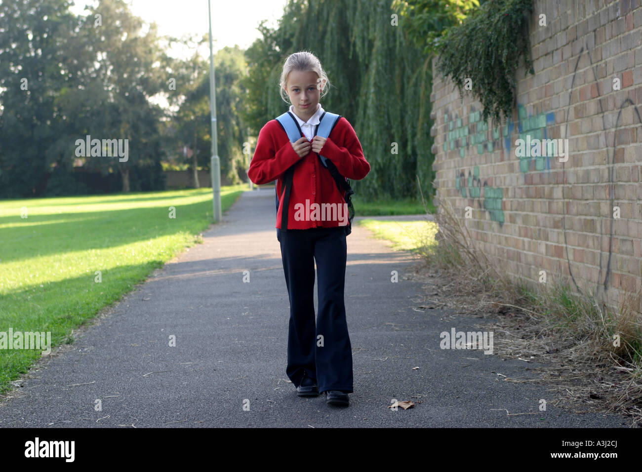 Girl on her way home from school walking past some graffiti Stock Photo ...