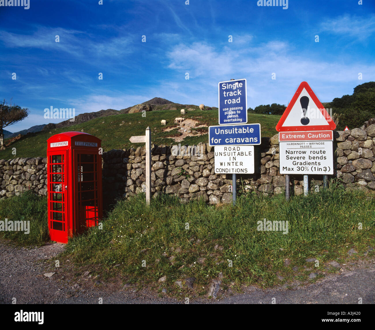 Red telephone box and road warning signs at foot of Hardknott Pass in ...