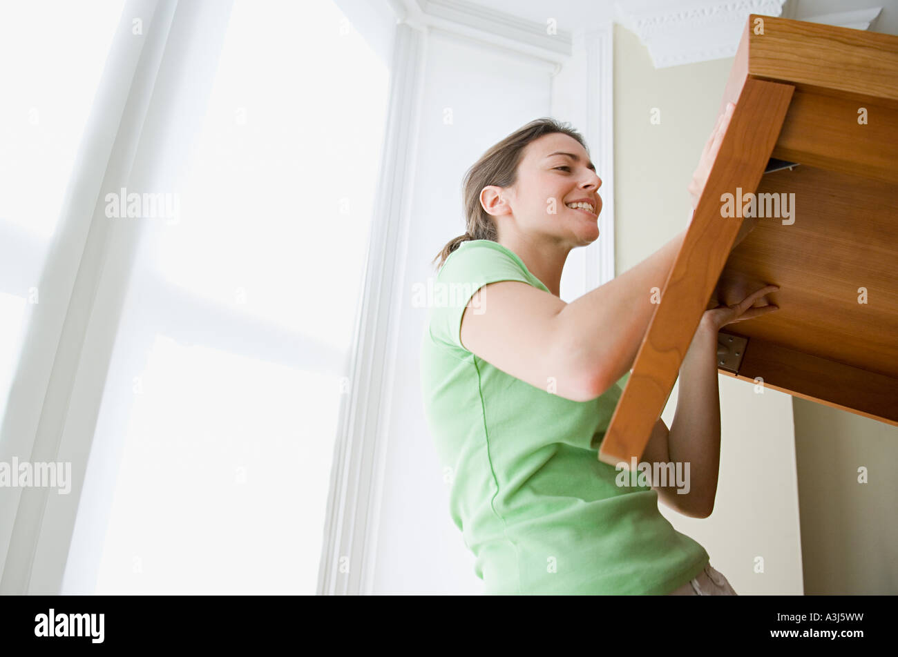 Woman lifting table Stock Photo - Alamy