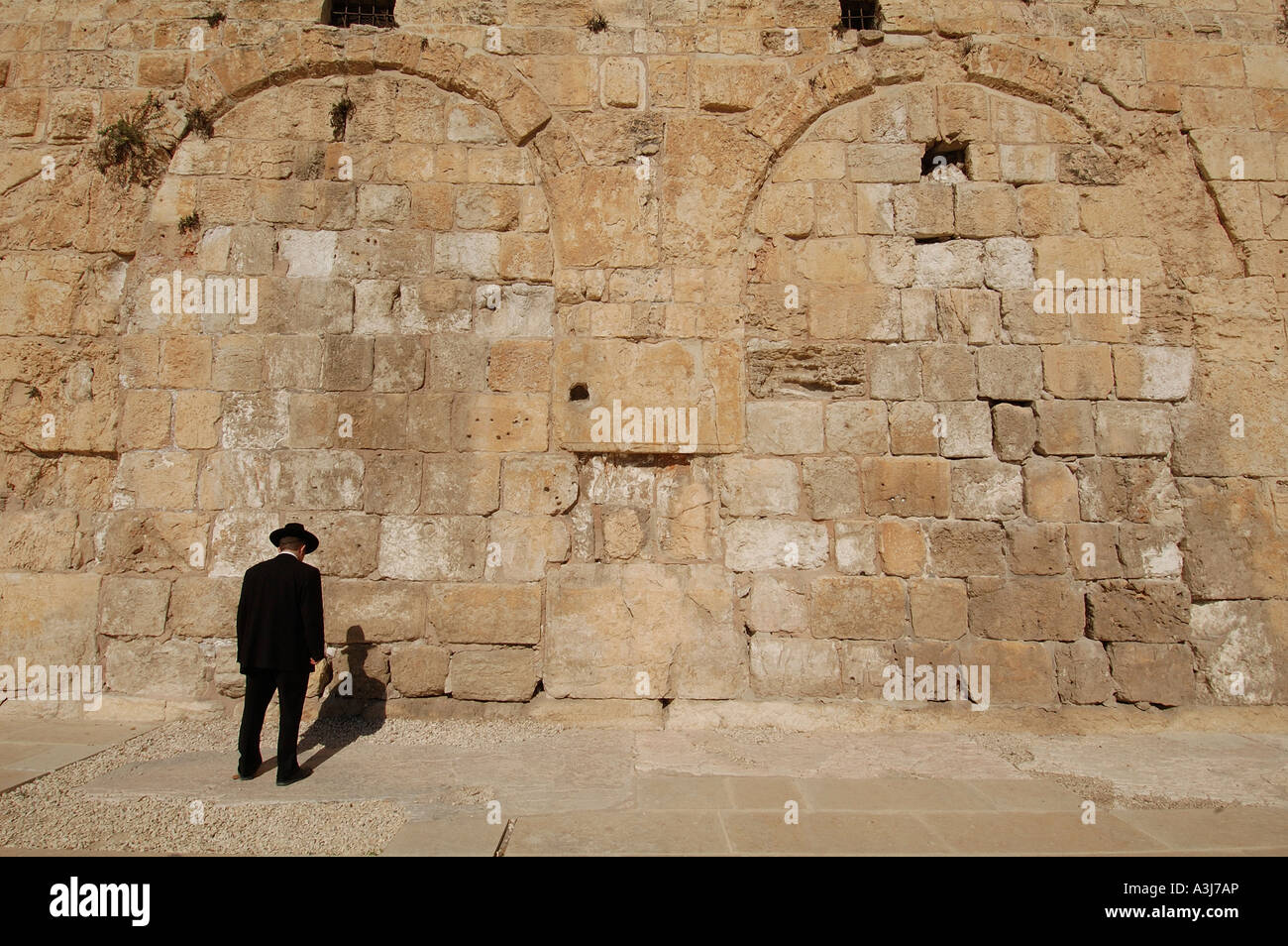An orthodox Jew standing in front of the now-blocked triple arched ...