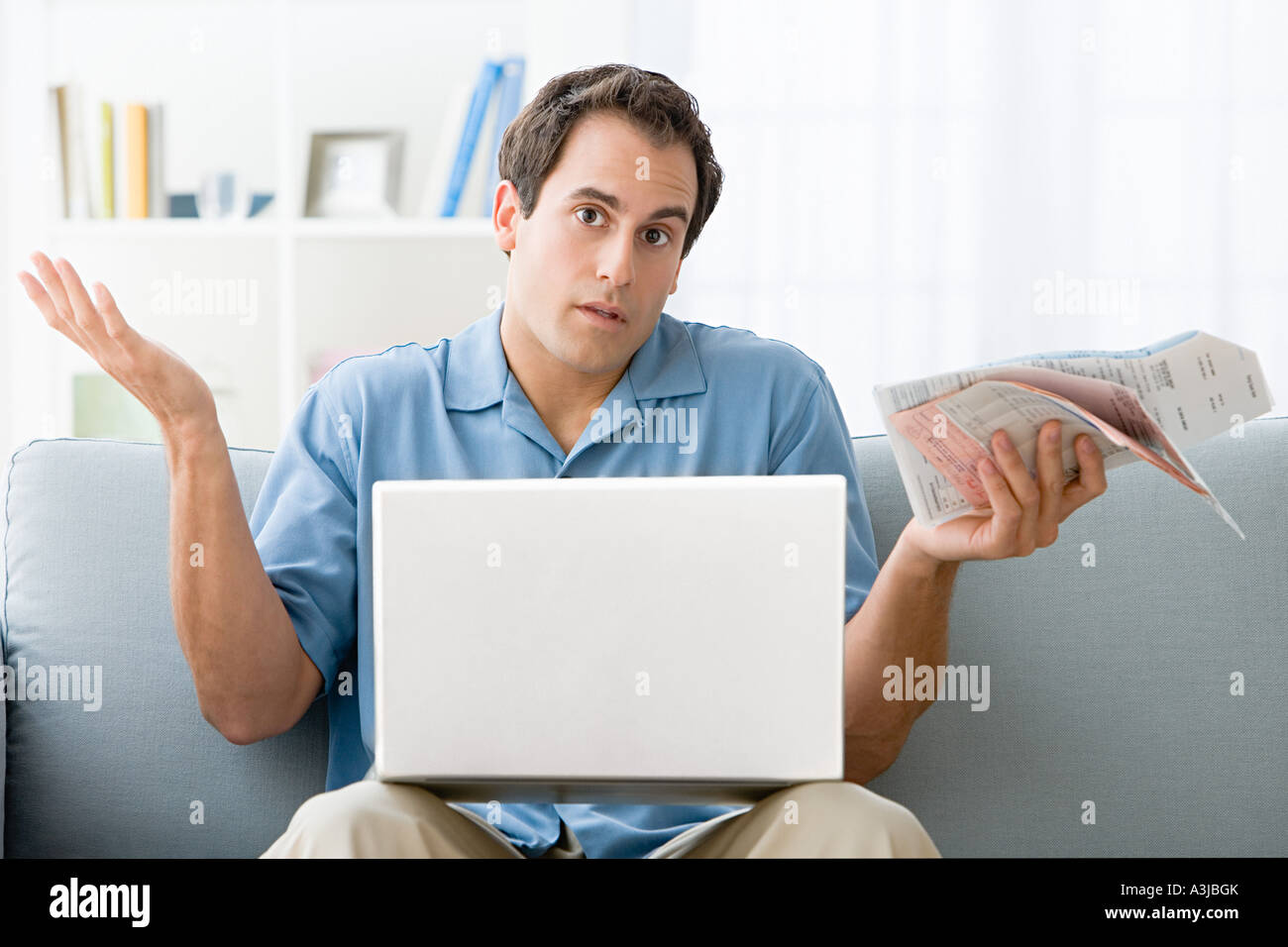 Man with bills and a laptop computer Stock Photo - Alamy