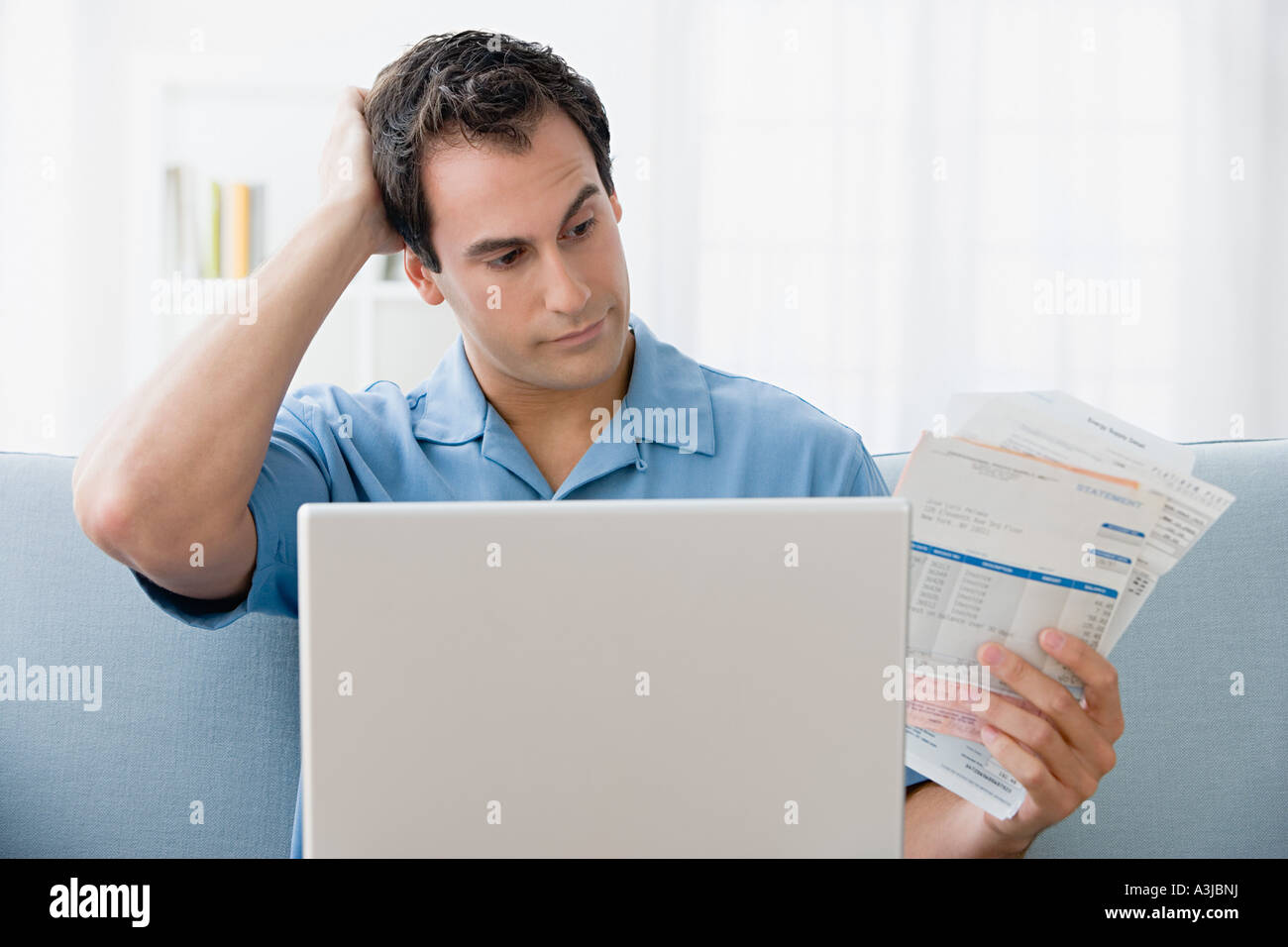 Man with bills and a laptop computer Stock Photo - Alamy