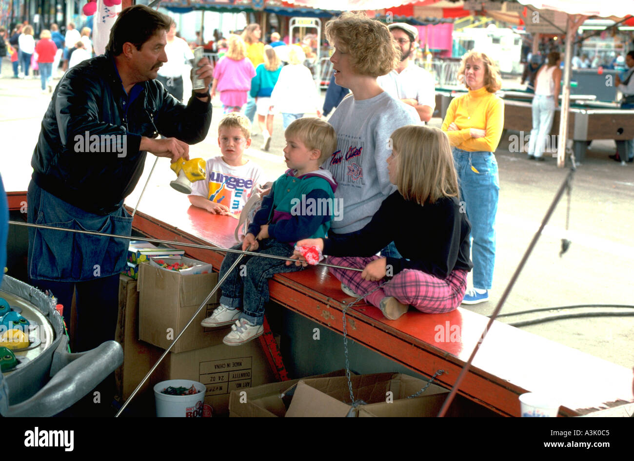 Carnival pitchman and mom with 3, 5 and 6 yr olds at MN State Fair. St ...