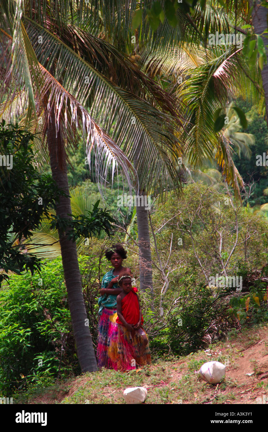 A member of Ipai custom village stands under a palm tree to escape the ...