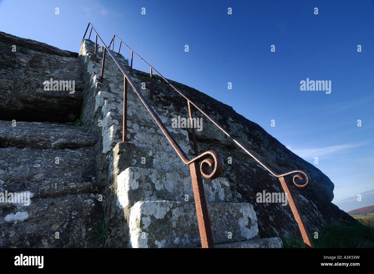 Granite stairs with rusting metal handrails leading up to clear blue ...