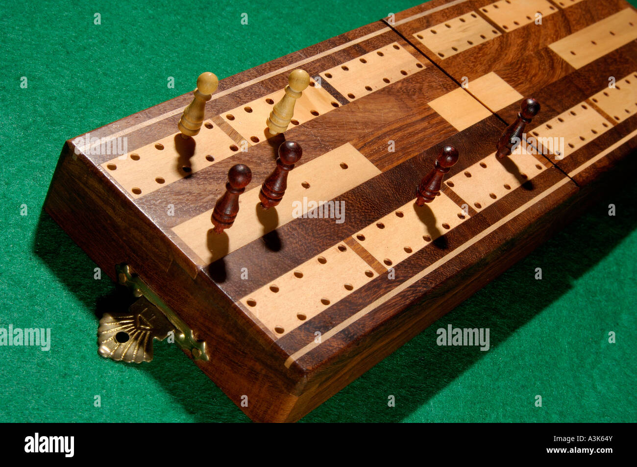 Traditional wooden cribbage board with wooden shaped pegs standing on ...
