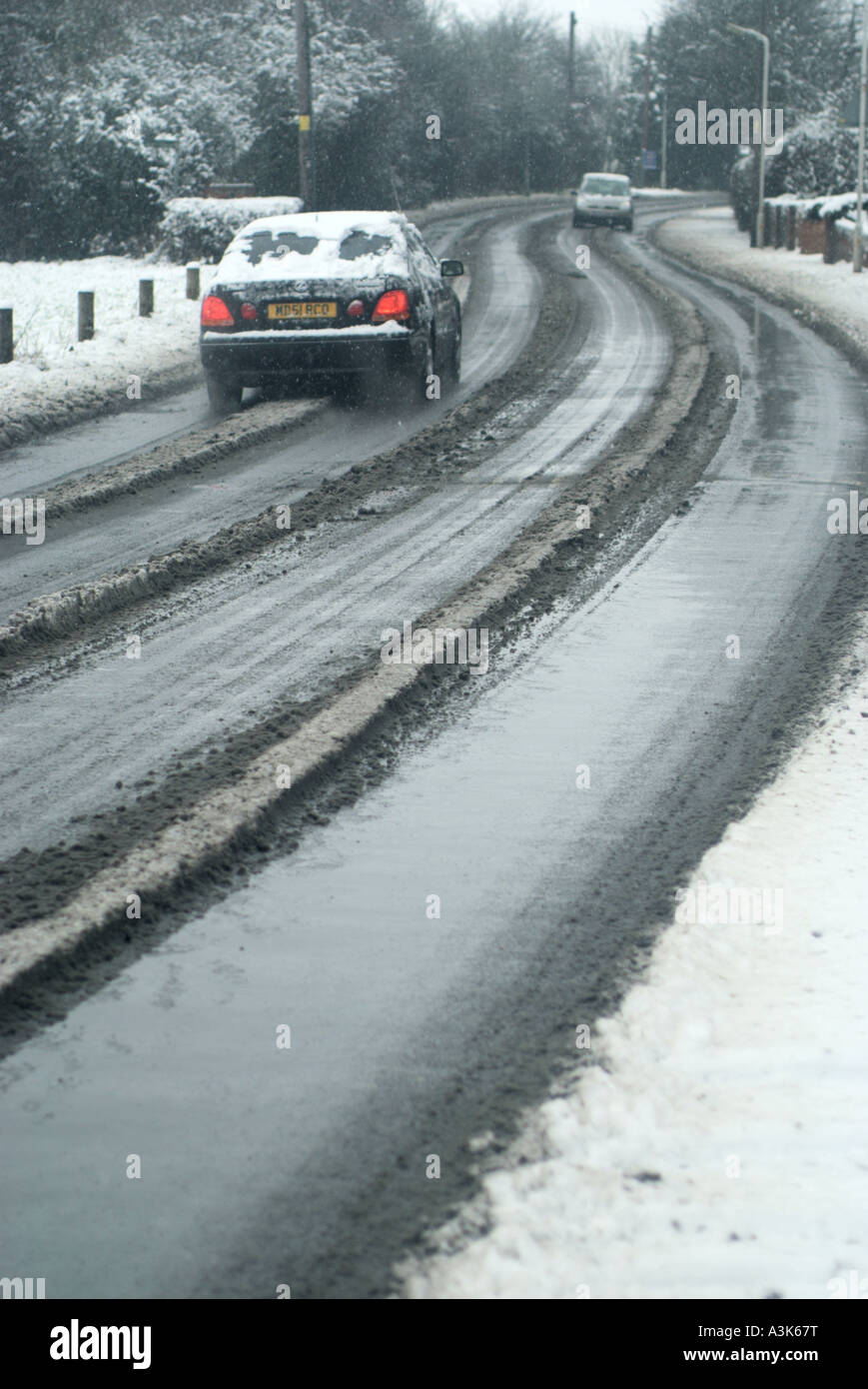 A car drives along a snow covered road during difficult driving ...