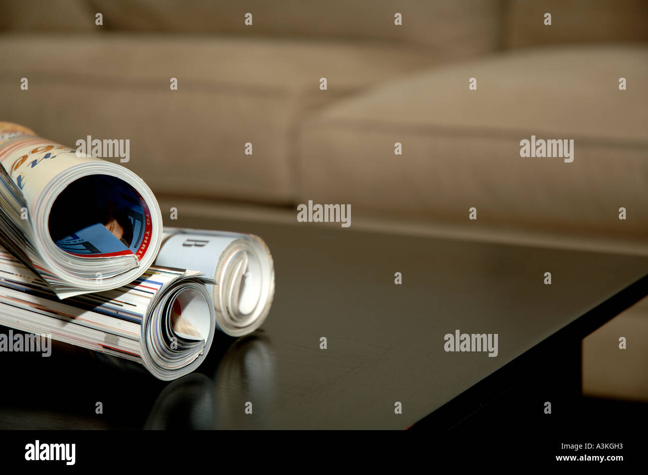 Rolled up magazines over coffee table Stock Photo - Alamy
