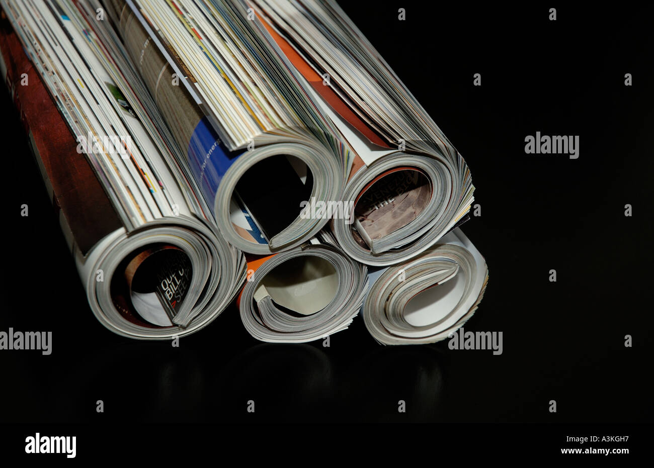 Rolled up magazines over black isolated background Stock Photo - Alamy